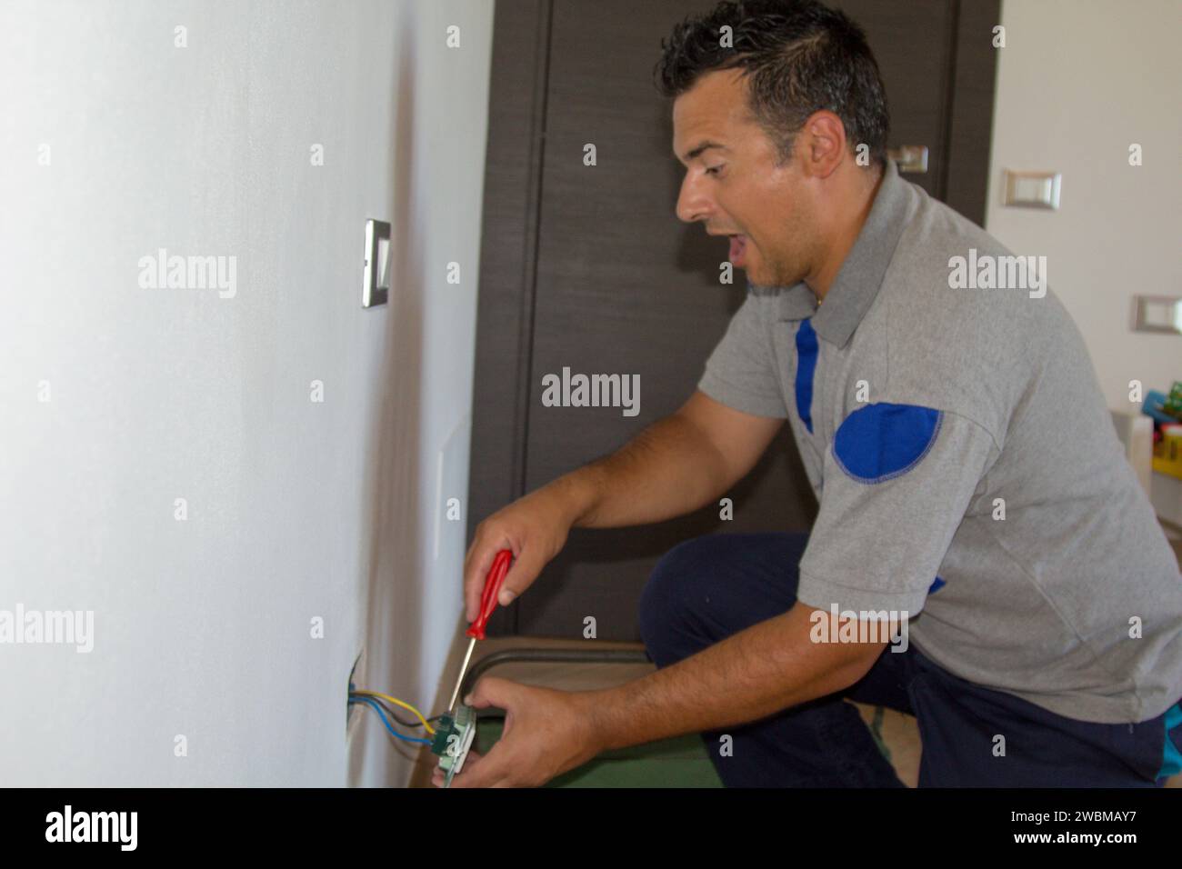 Image of an electrician as he installs an electrical plug and gets an ...
