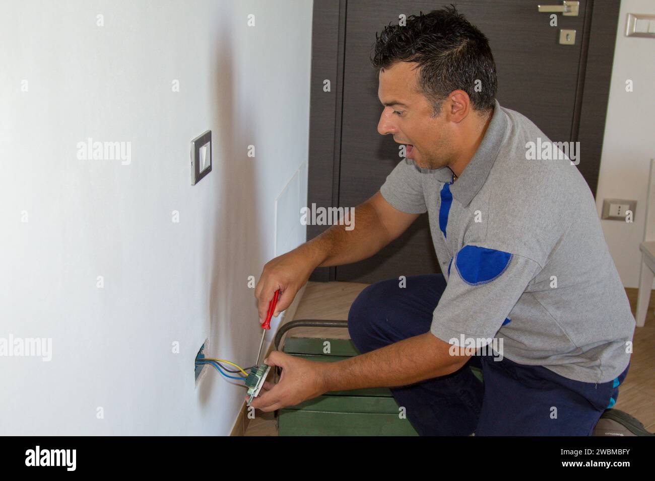 Image of an electrician as he installs an electrical plug and gets an ...