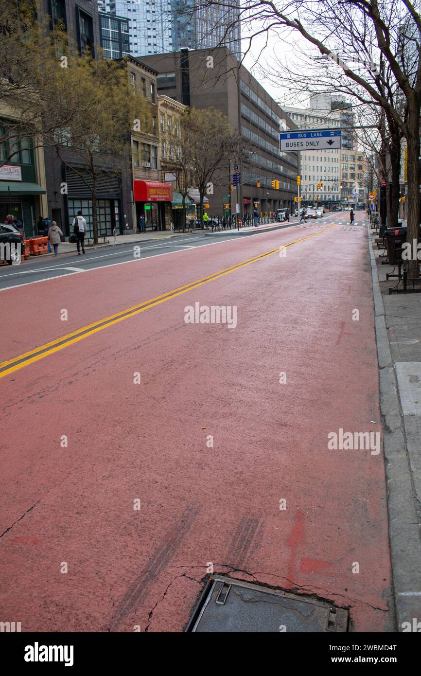 A city street has two lanes of red asphalt in parallel, with a manhole ...