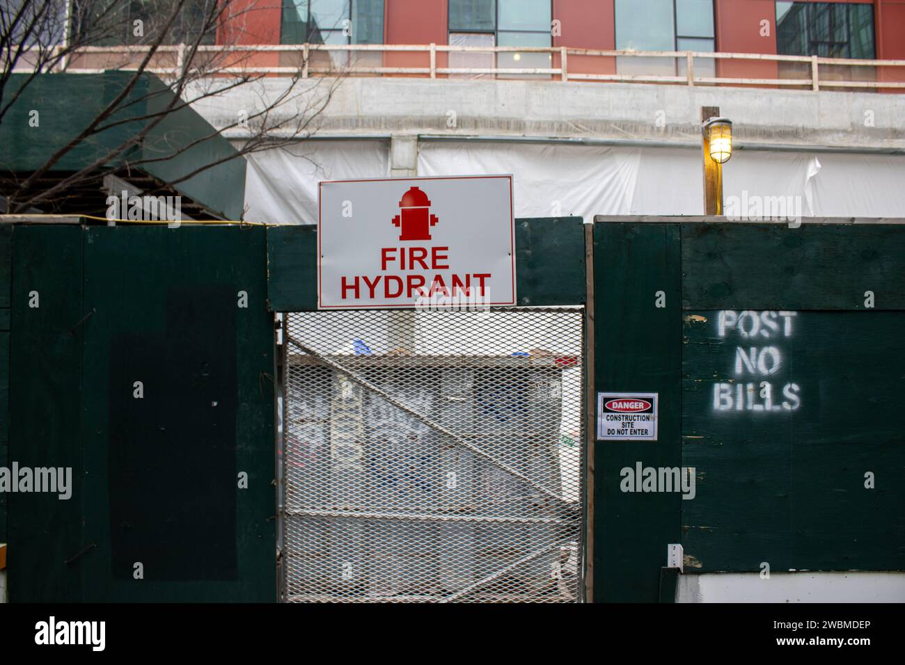 A vivid red sign is attached to a metal gate, directly above a bright ...