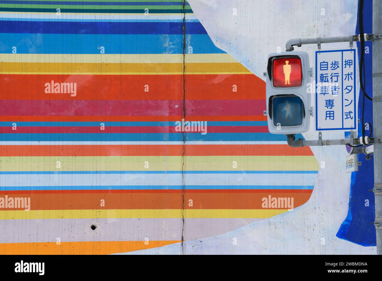Red traffic light against a vibrant, colorful striped wall with Asian ...