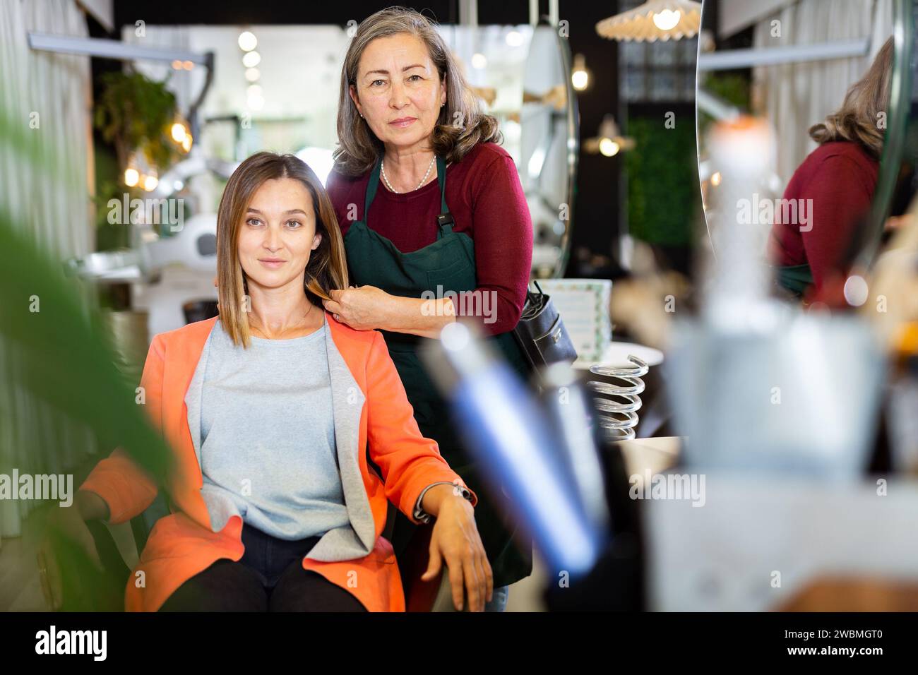Elderly woman hair stylist discussing new hairdo with female customer ...