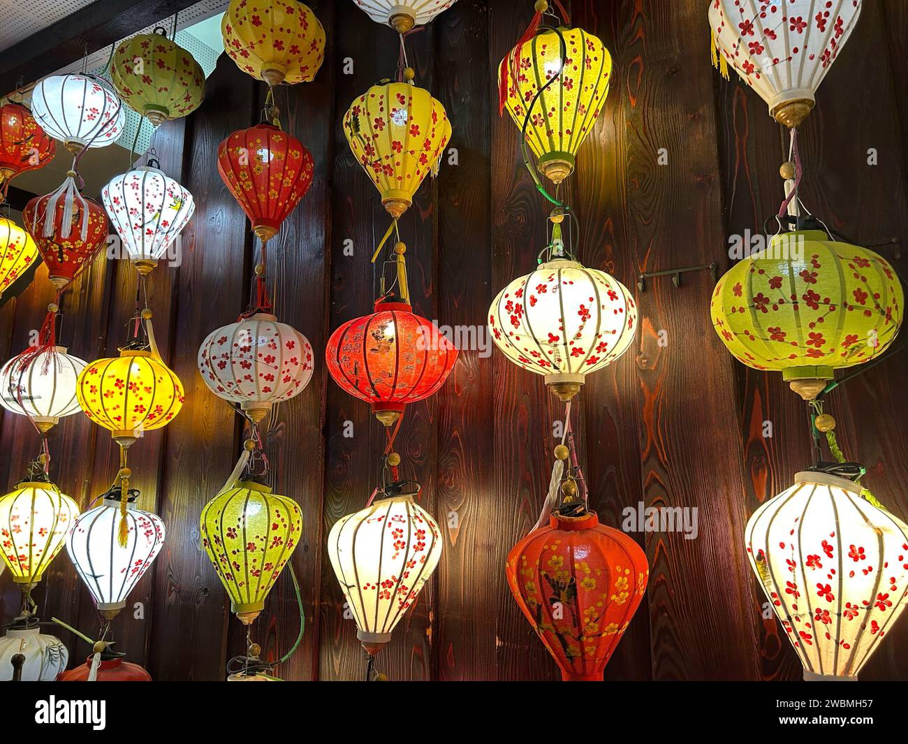 A selection of colorful paper lanterns suspended from the ceiling above ...