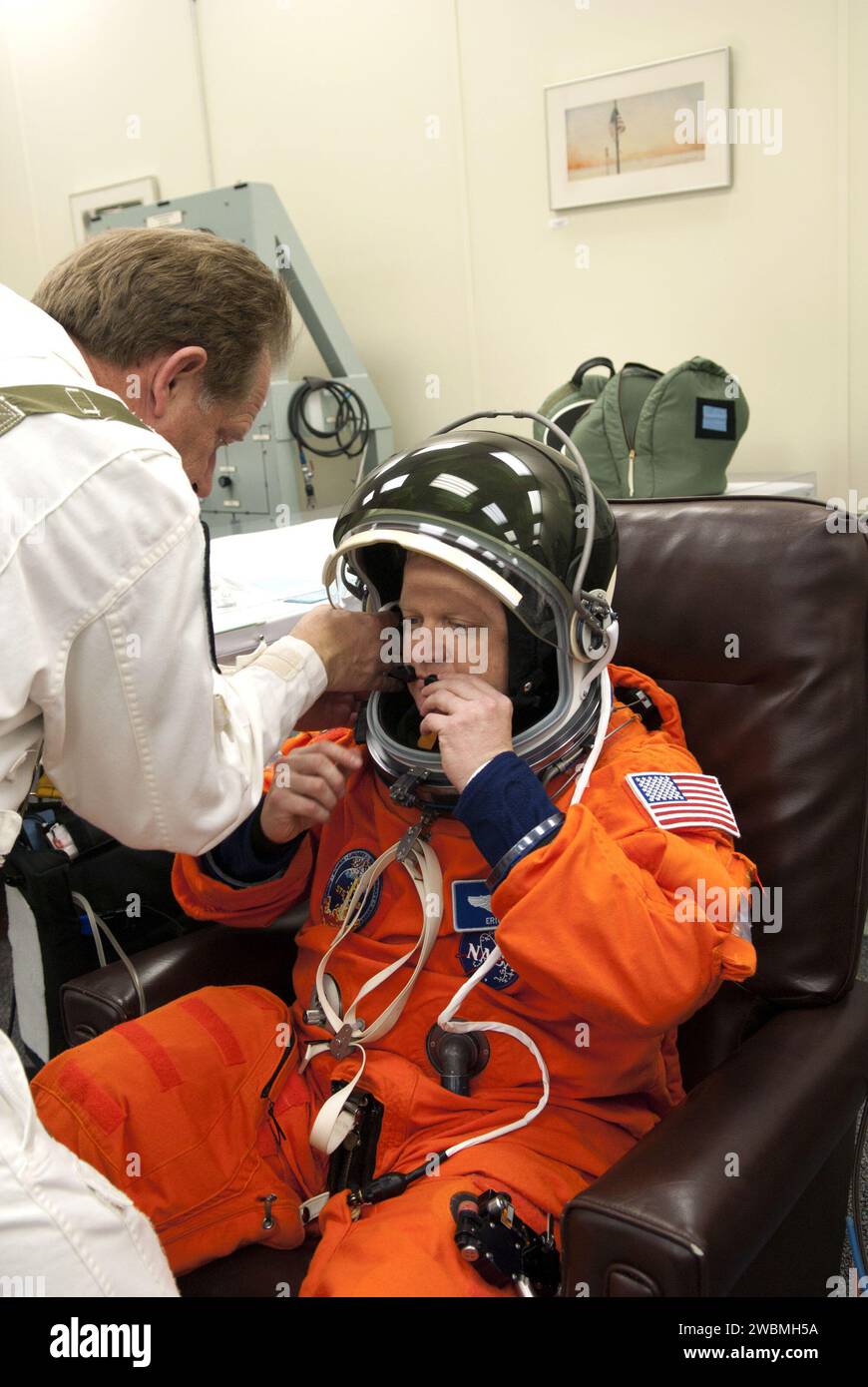 STS-133 crew members put on launch-and-entry suits, checking helmets ...