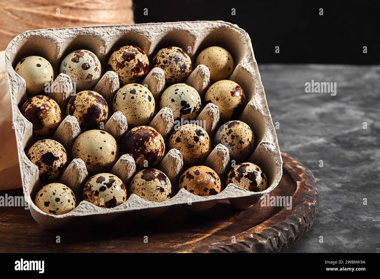 Quail eggs in a gray cardboard box. Close-up photo. Black concrete ...