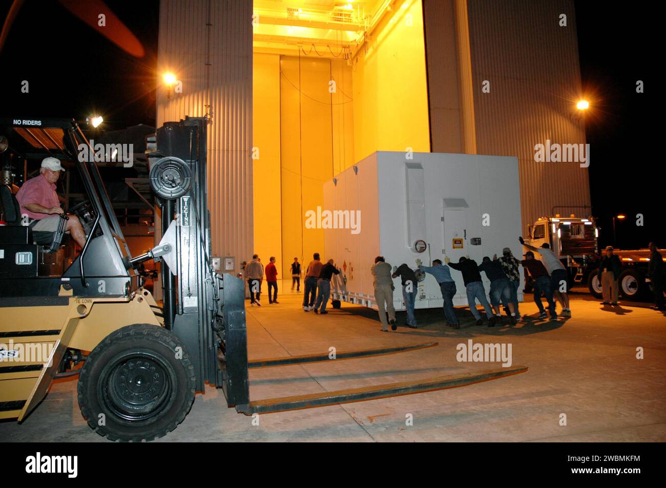 KENNEDY SPACE CENTER, FLA. - Workers roll one of two containers with ...
