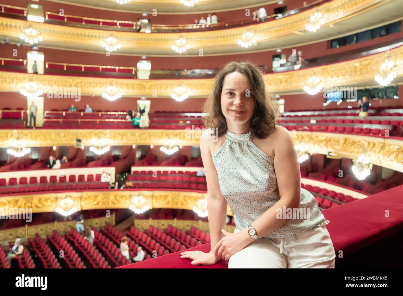 Woman after watching performance poses in auditorium balcony of opera ...