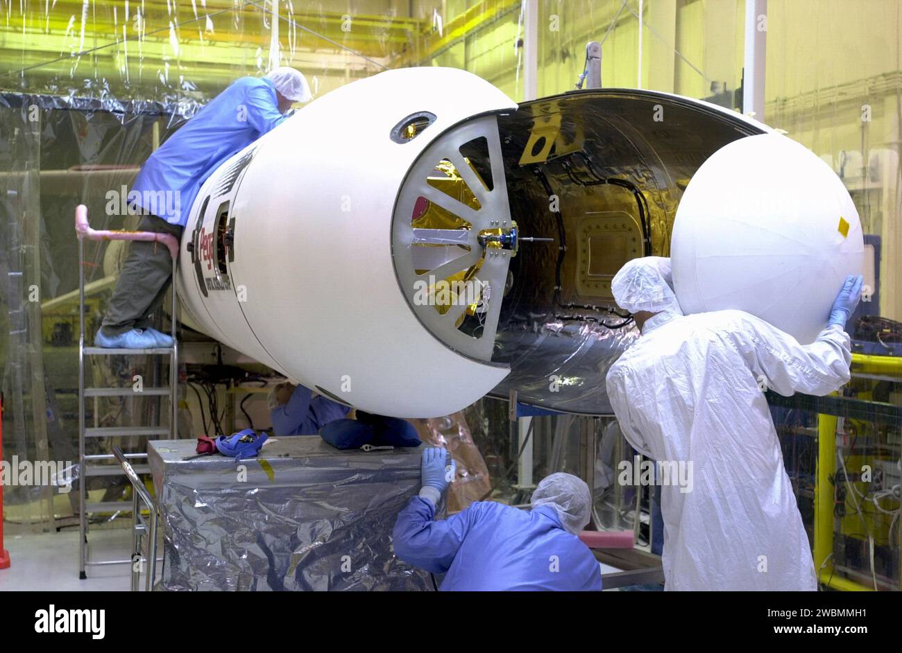 Technicians at Vandenberg AFB position the second fairing half around ...