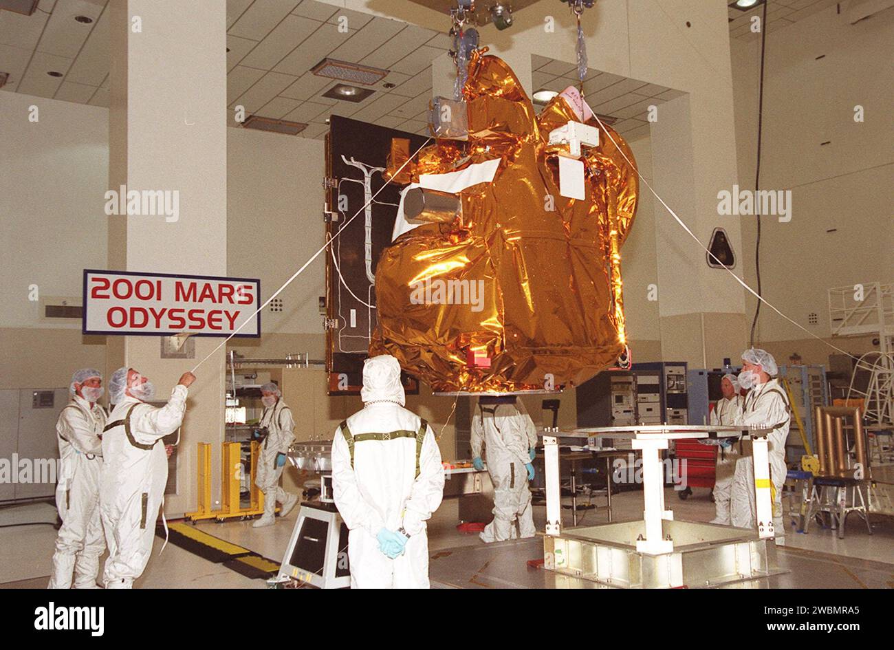 With workers keeping watch, the 2001 Mars Odyssey Orbiter, suspended by ...