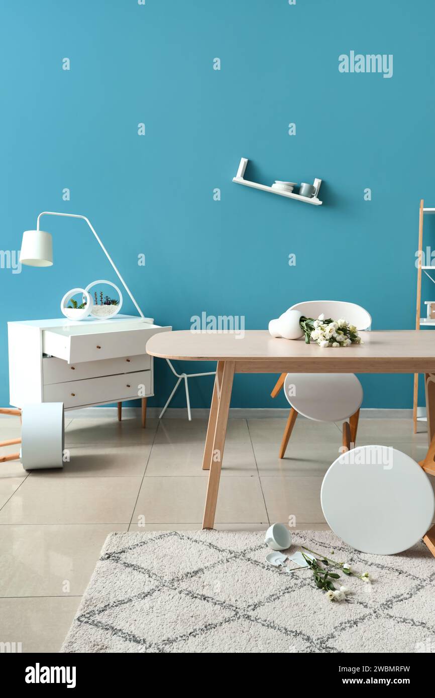 Dining table with fallen vase and flowers in messy room Stock Photo - Alamy