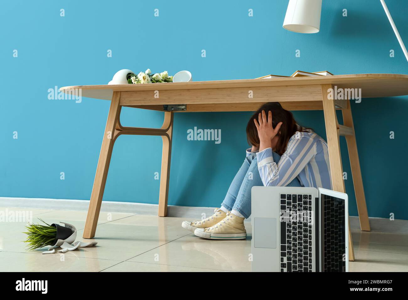 Young woman hiding under table during earthquake in office Stock Photo ...