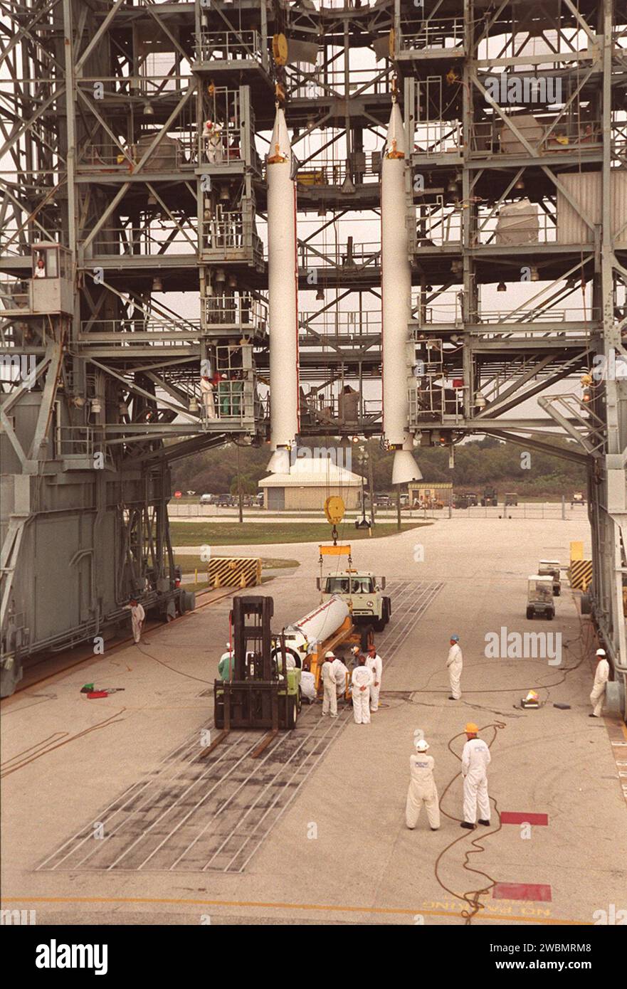 Two solid rocket boosters, in the background, are lifted up the gantry ...