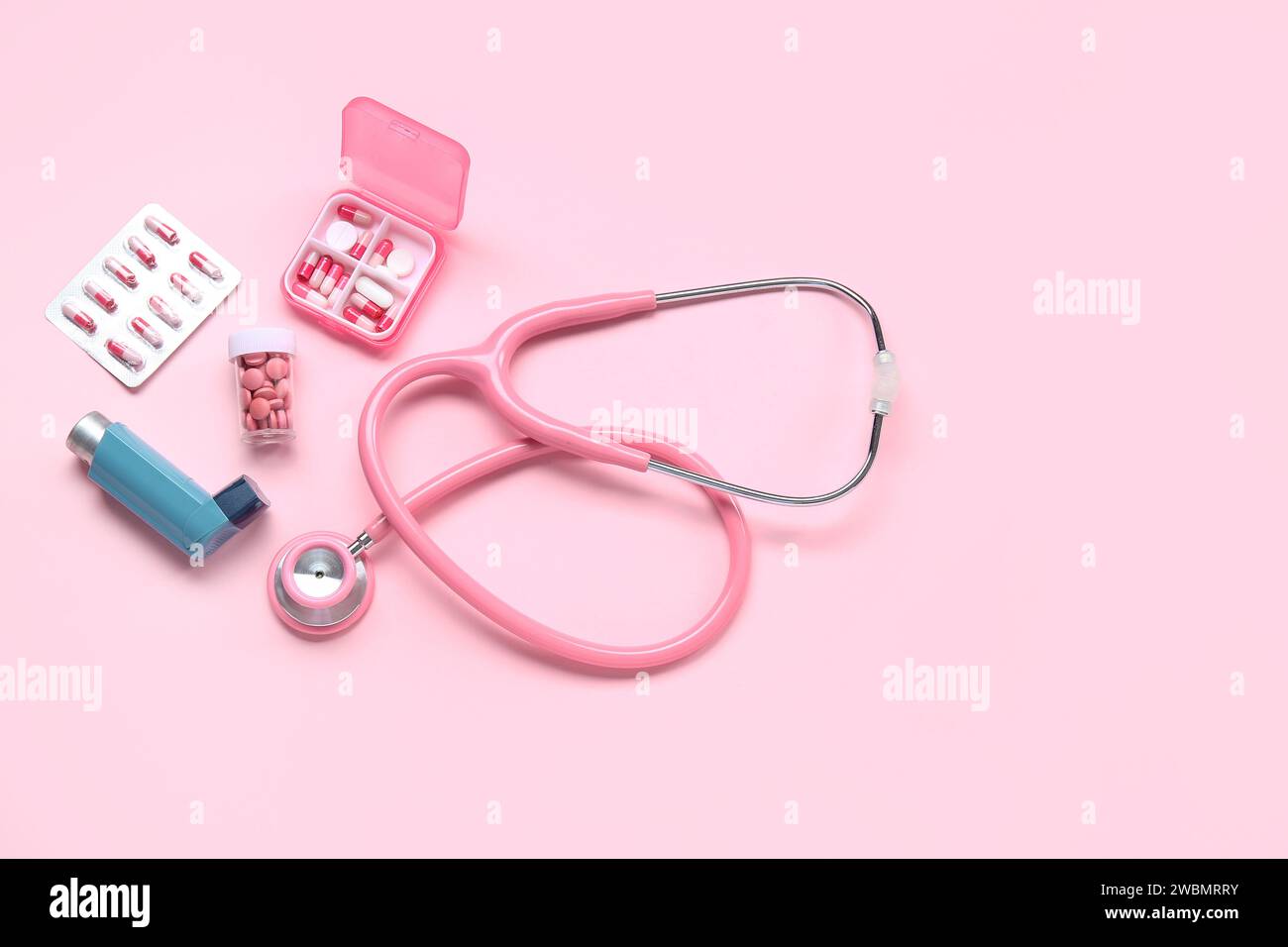 Composition with asthma inhaler, stethoscope and boxes of pills on pink ...