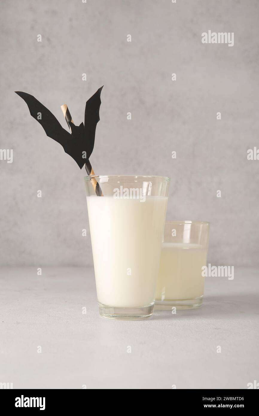 Glasses of milk and bat made of paper for Halloween on light background ...