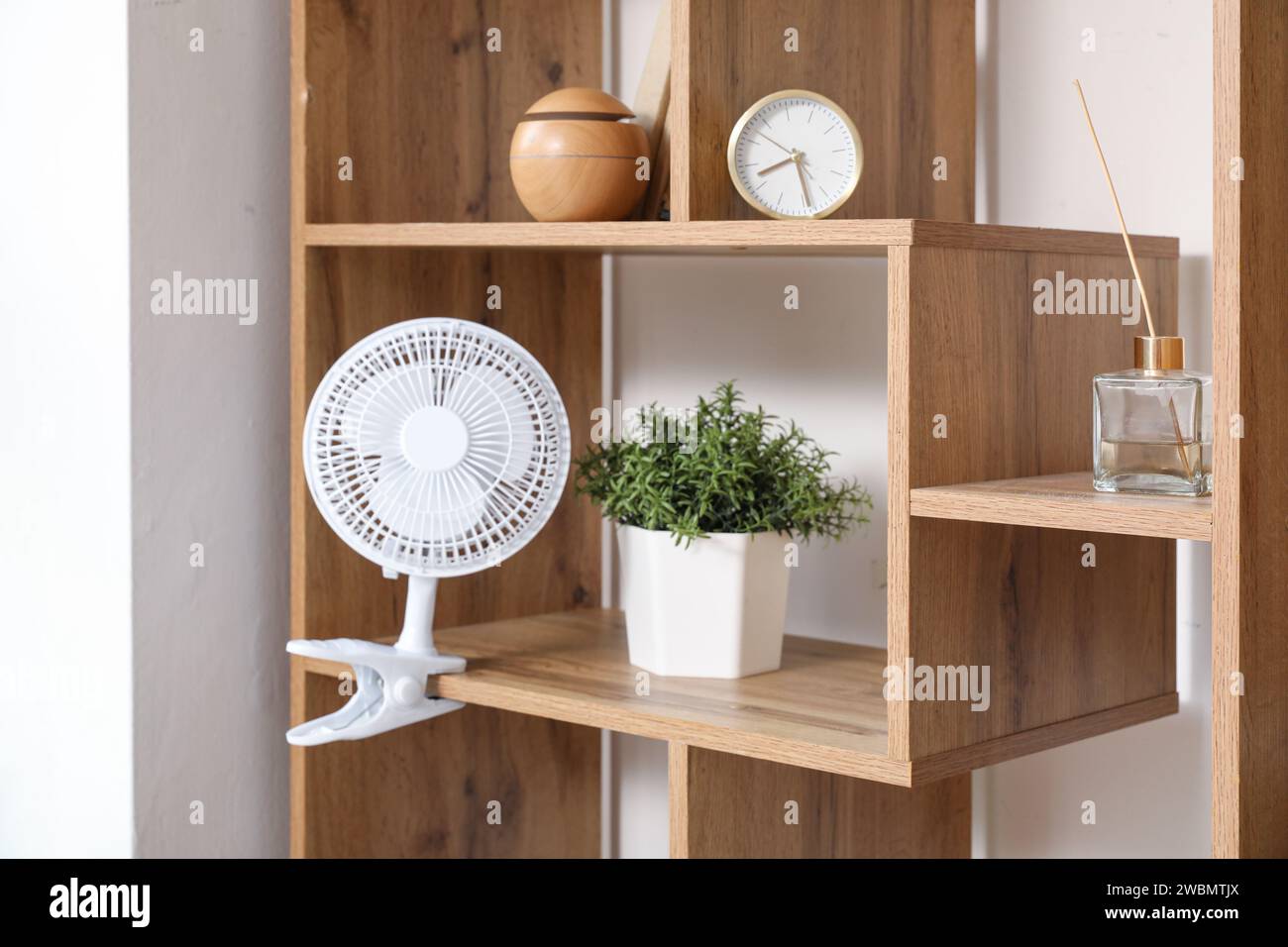 Electric fan with houseplant on shelf in living room Stock Photo - Alamy