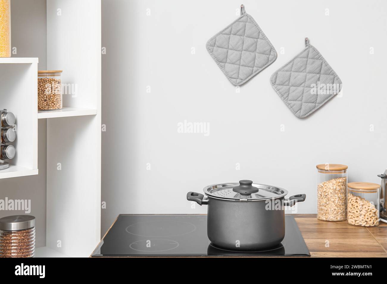 Wooden kitchen countertop with utensils and cooking pot on electric ...