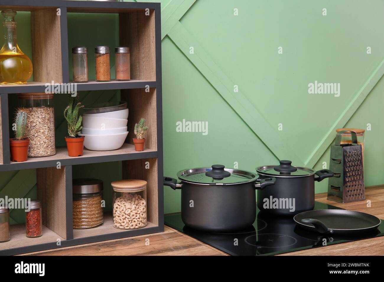 Wooden countertop with electric stove, cooking pots and shelving unit ...