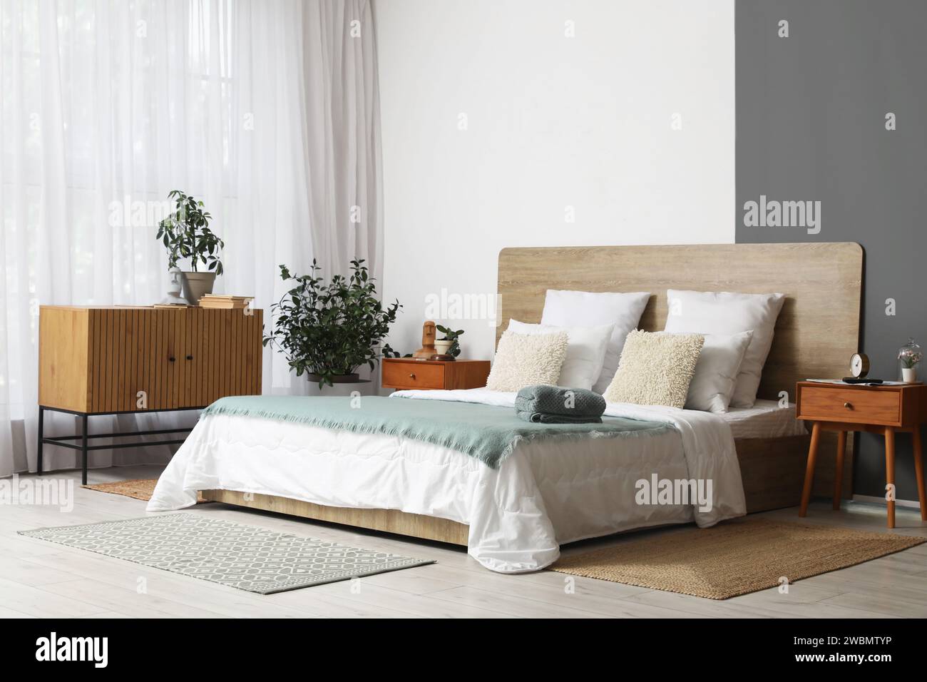 Interior of modern bedroom with wooden bed, houseplants and alarm clock ...
