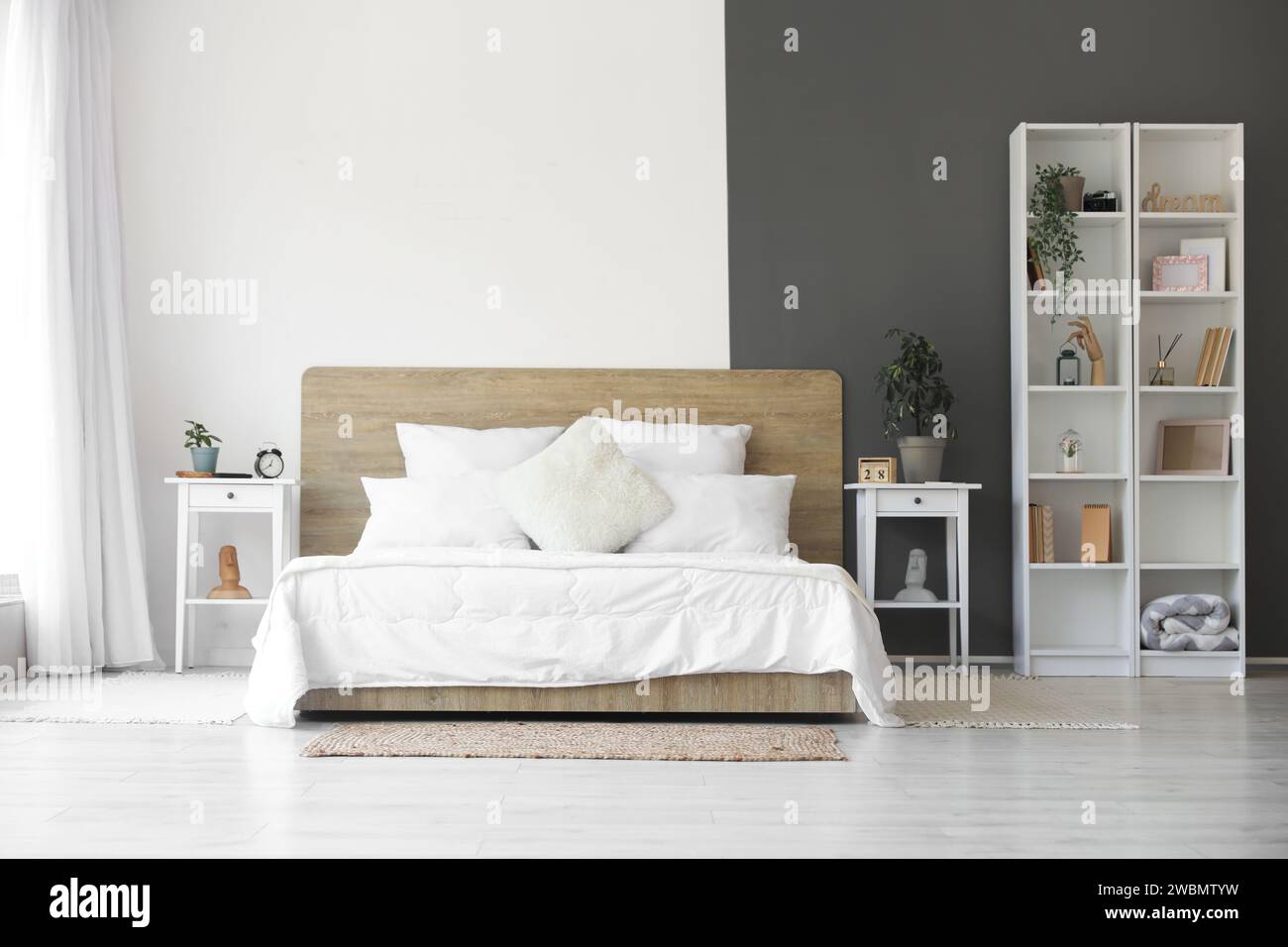 Interior of modern bedroom with white bed and alarm clock on bedside ...