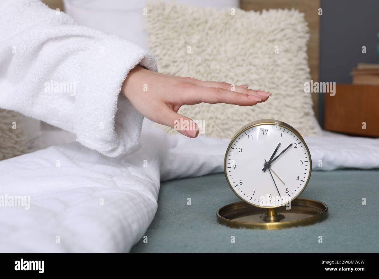 Female hand turning off alarm clock on bed, closeup Stock Photo - Alamy
