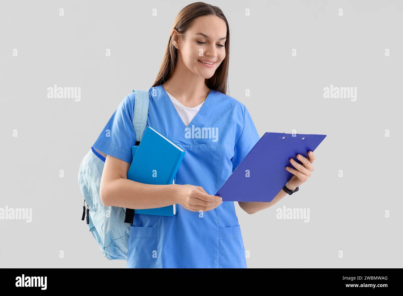 Female medical intern with clipboard on light background Stock Photo ...
