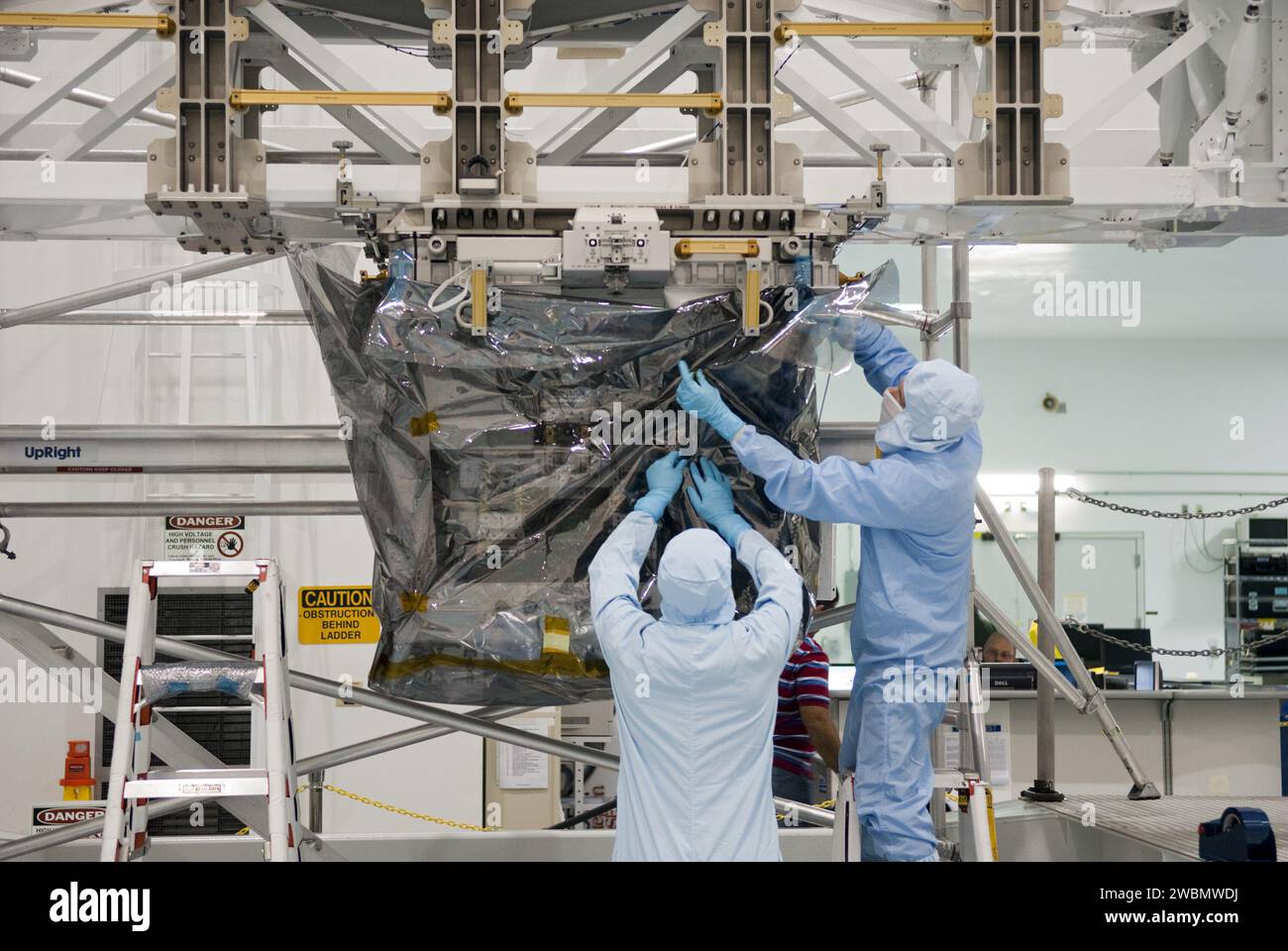 Technicians at NASA's Space Station Processing Facility install a ...