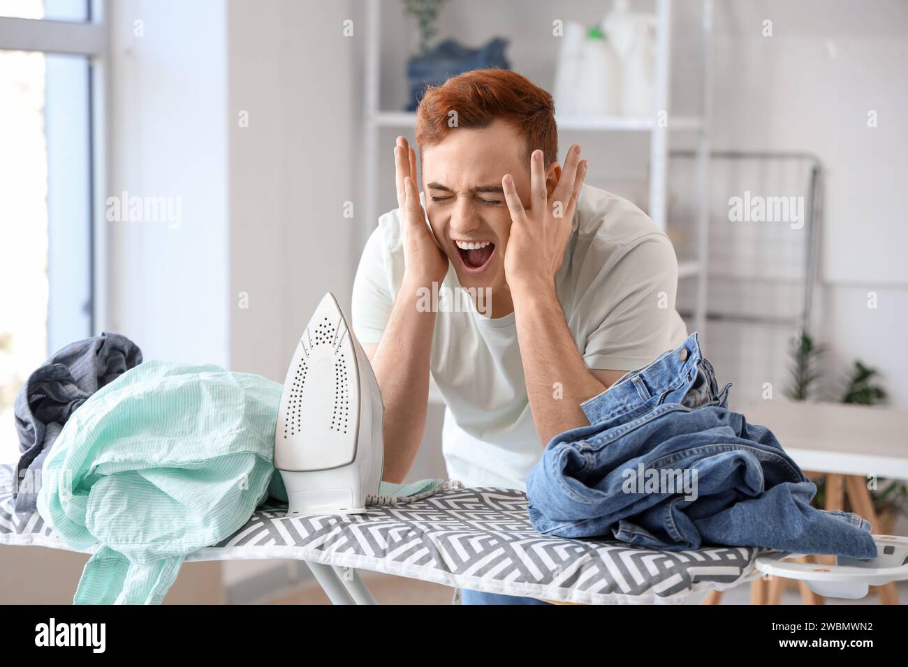 Stressed young man with electric iron and crumpled clothes leaning on ...