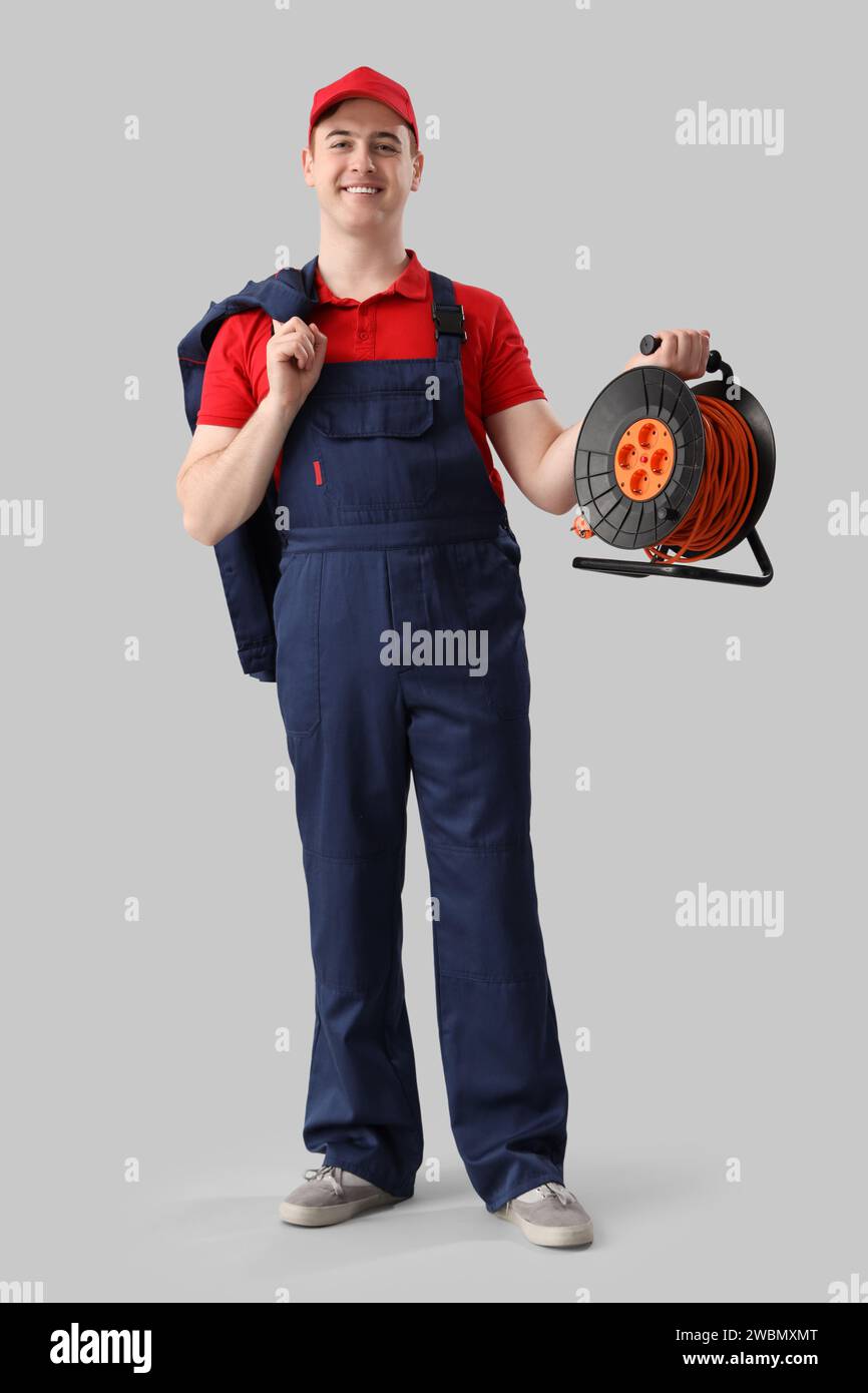 Male electrician with extension cord reel on light background Stock ...