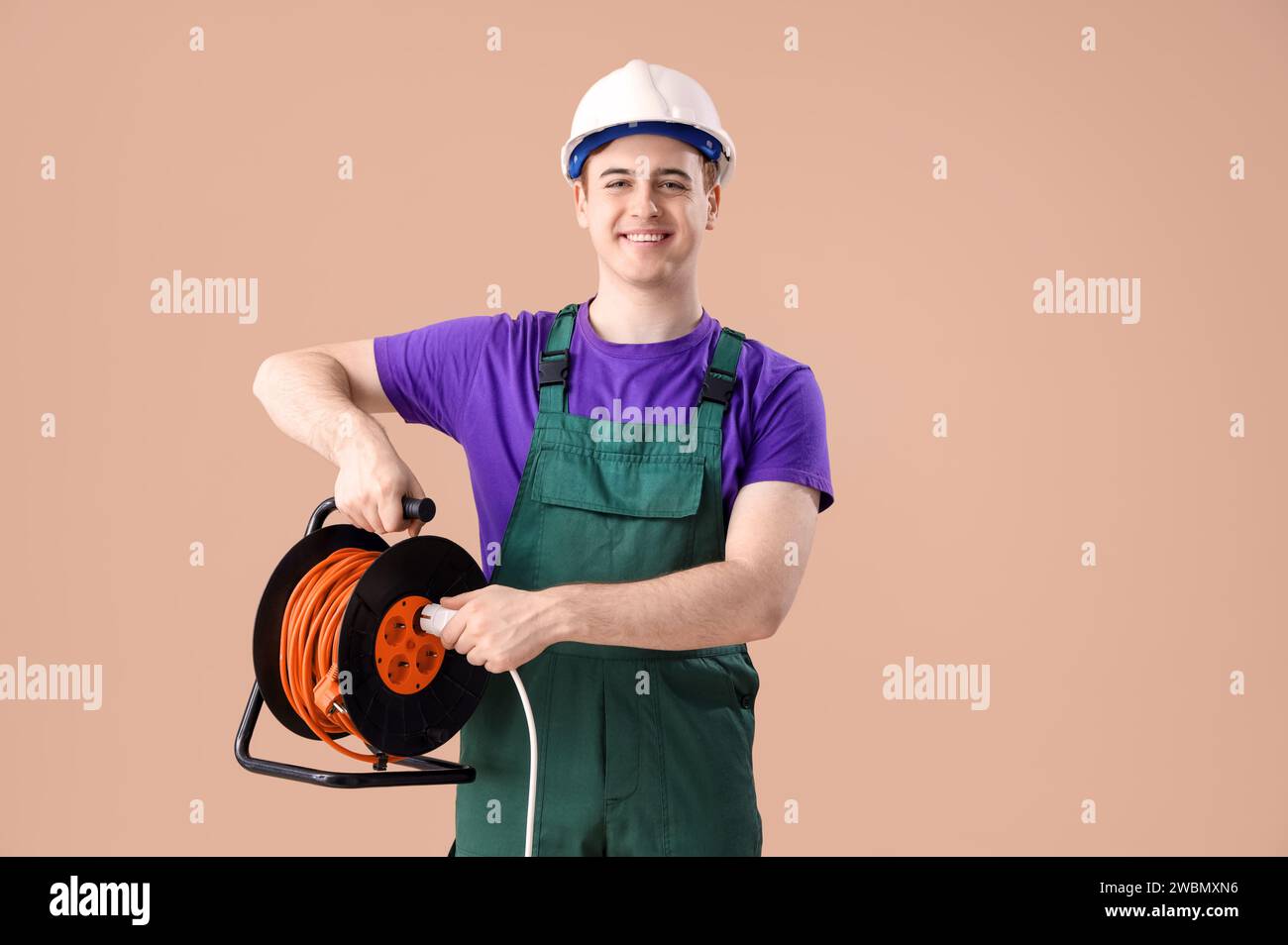 Male electrician with extension cord reel on brown background Stock ...
