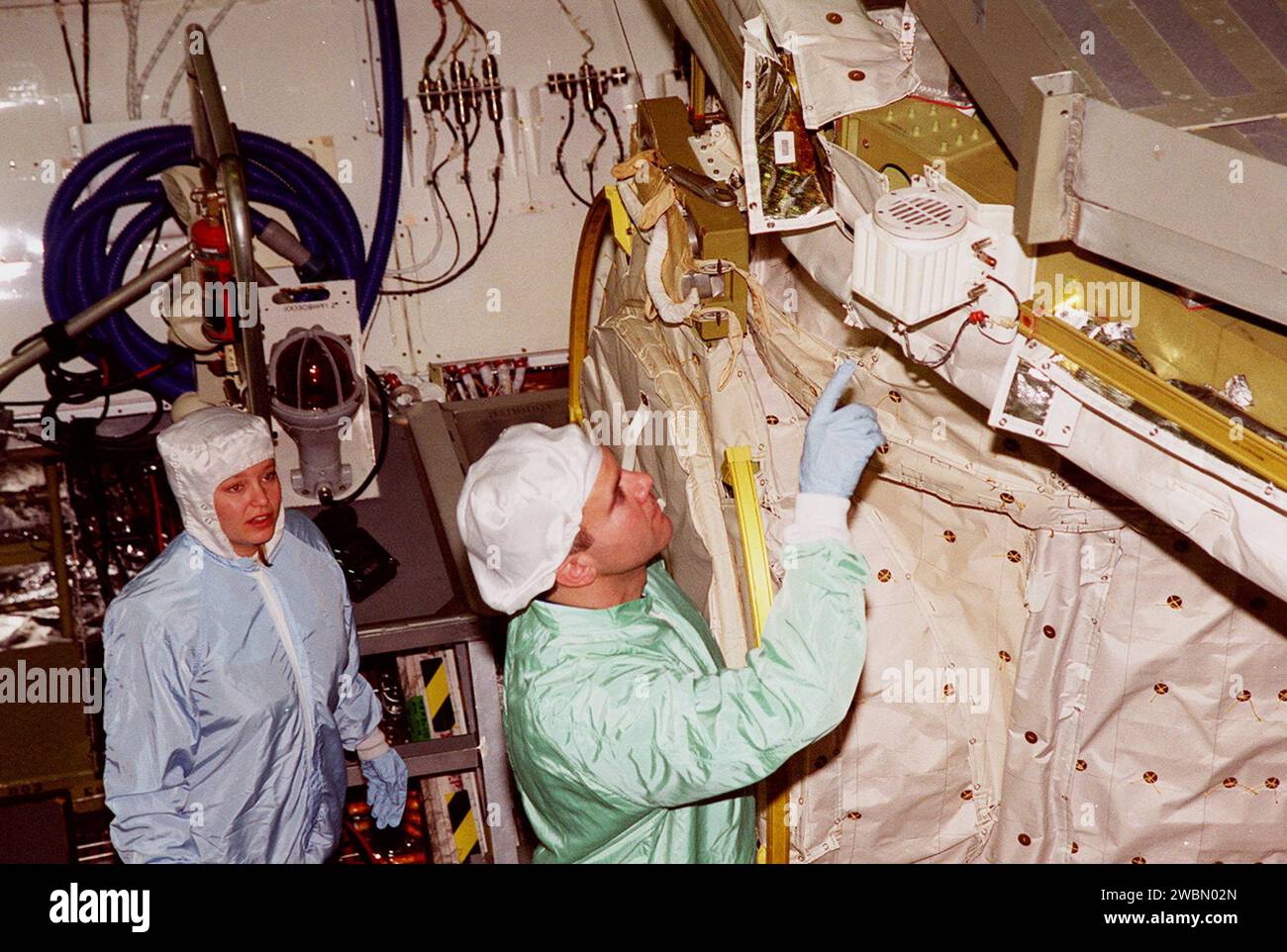In the Orbiter Processing Facility bay 1, STS-102 Pilot James W. Kelly (right) points to a piece ...