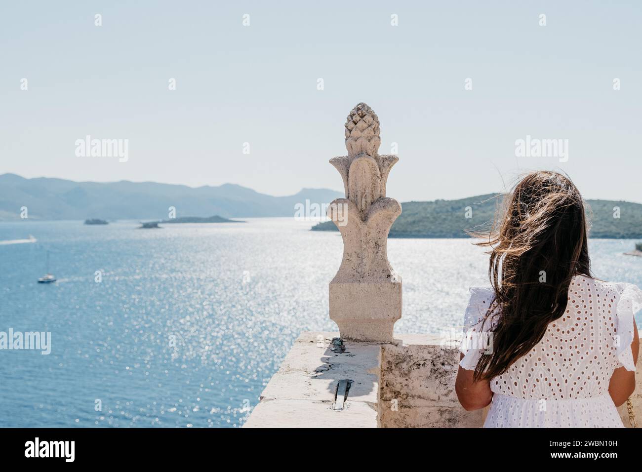 A young girl stands by the waterfront, gazing pensively at the ...
