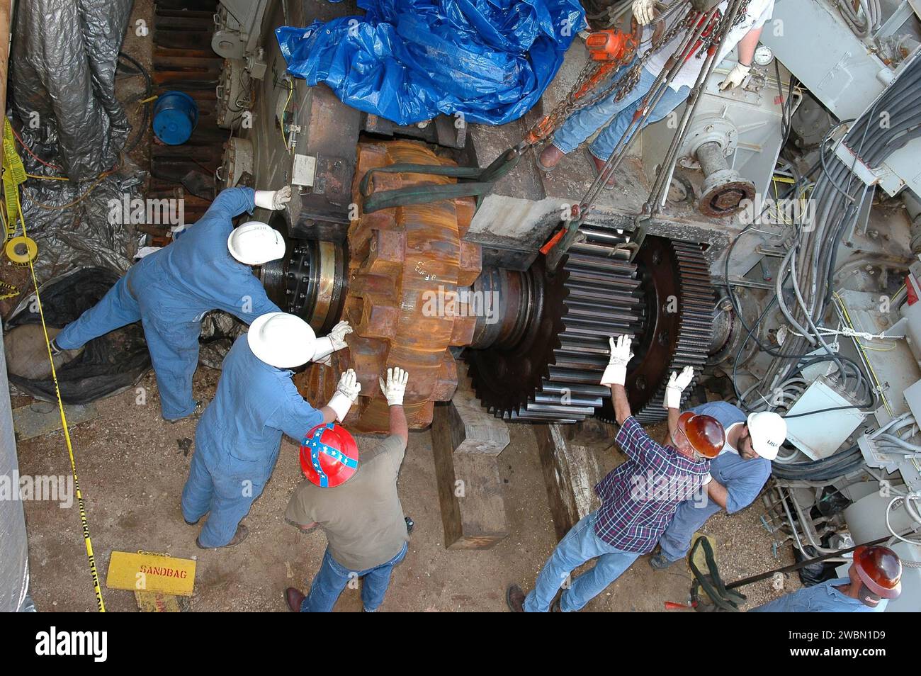KENNEDY SPACE CENTER, FLA. - Workers maneuver the giant sprocket (left ...