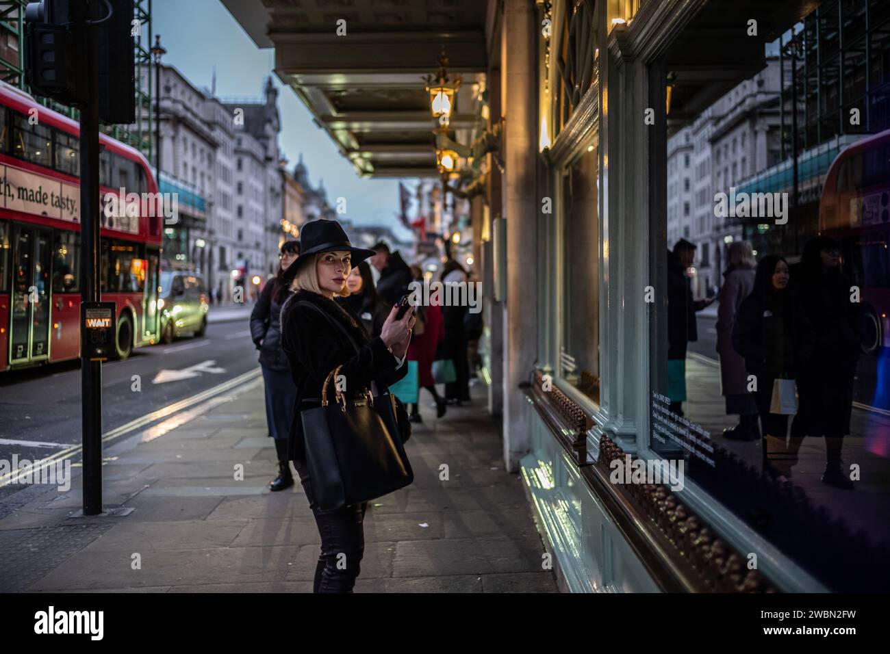 A woman takes a photograph of Fortum & Mason luxury department store window on Piccadilly, in ...