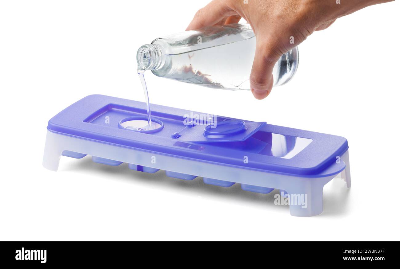 Clean water pours into a mold for ice cubes, white background. Ice tray ...