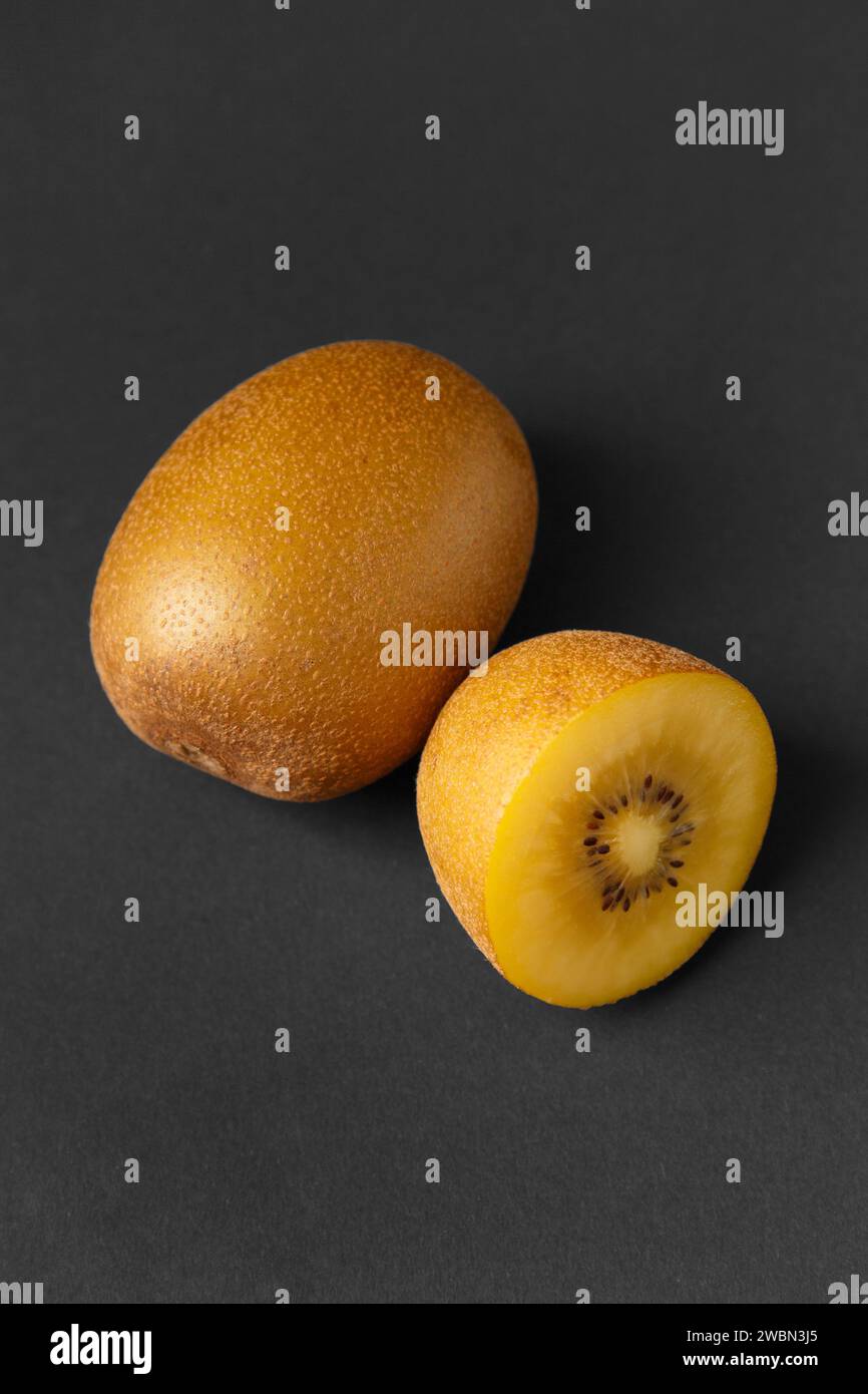 Whole and halved ripe golden kiwi isolated on a black background. Kiwi ...