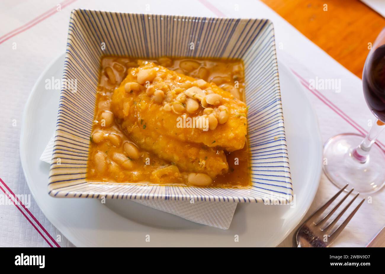 Large piece of lean cod fillet stewed in bean gravy Stock Photo - Alamy