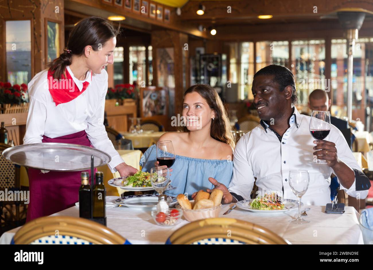 Young waitress bringing dishes to couple at restaurant Stock Photo - Alamy