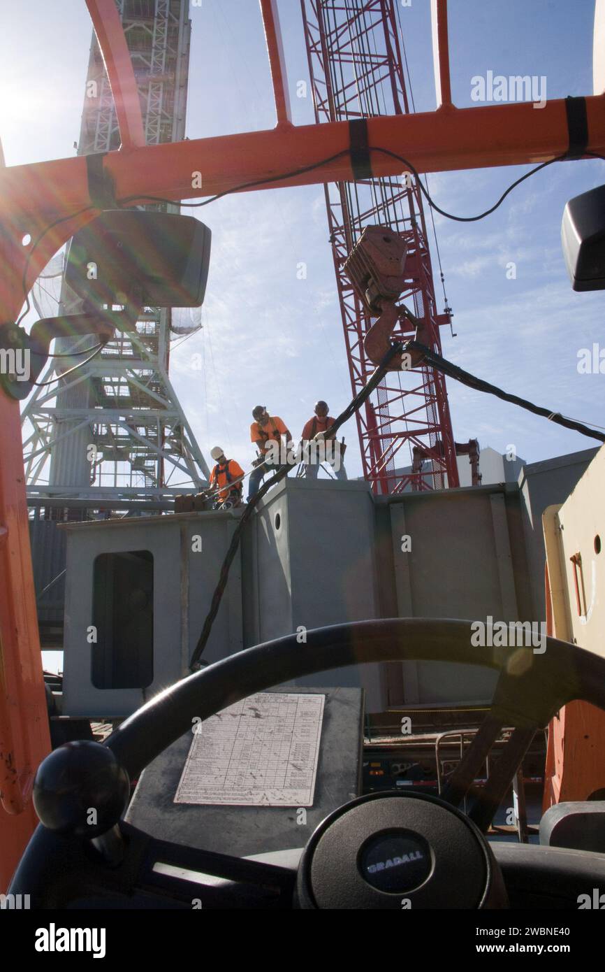Workers at Kennedy Space Center attach a crane to the fourth segment of ...