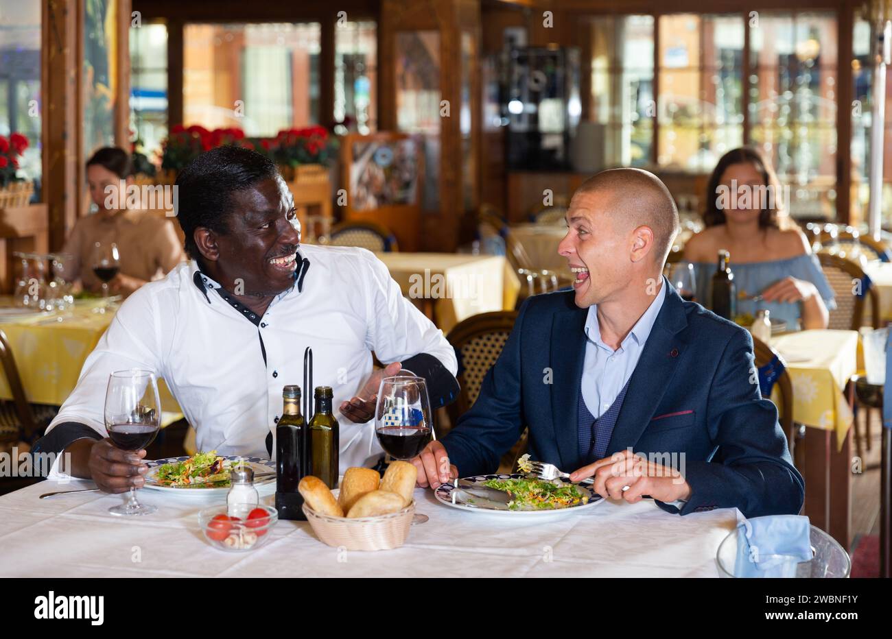 Two handsome men in classic suits having dinner at restaurant Stock ...