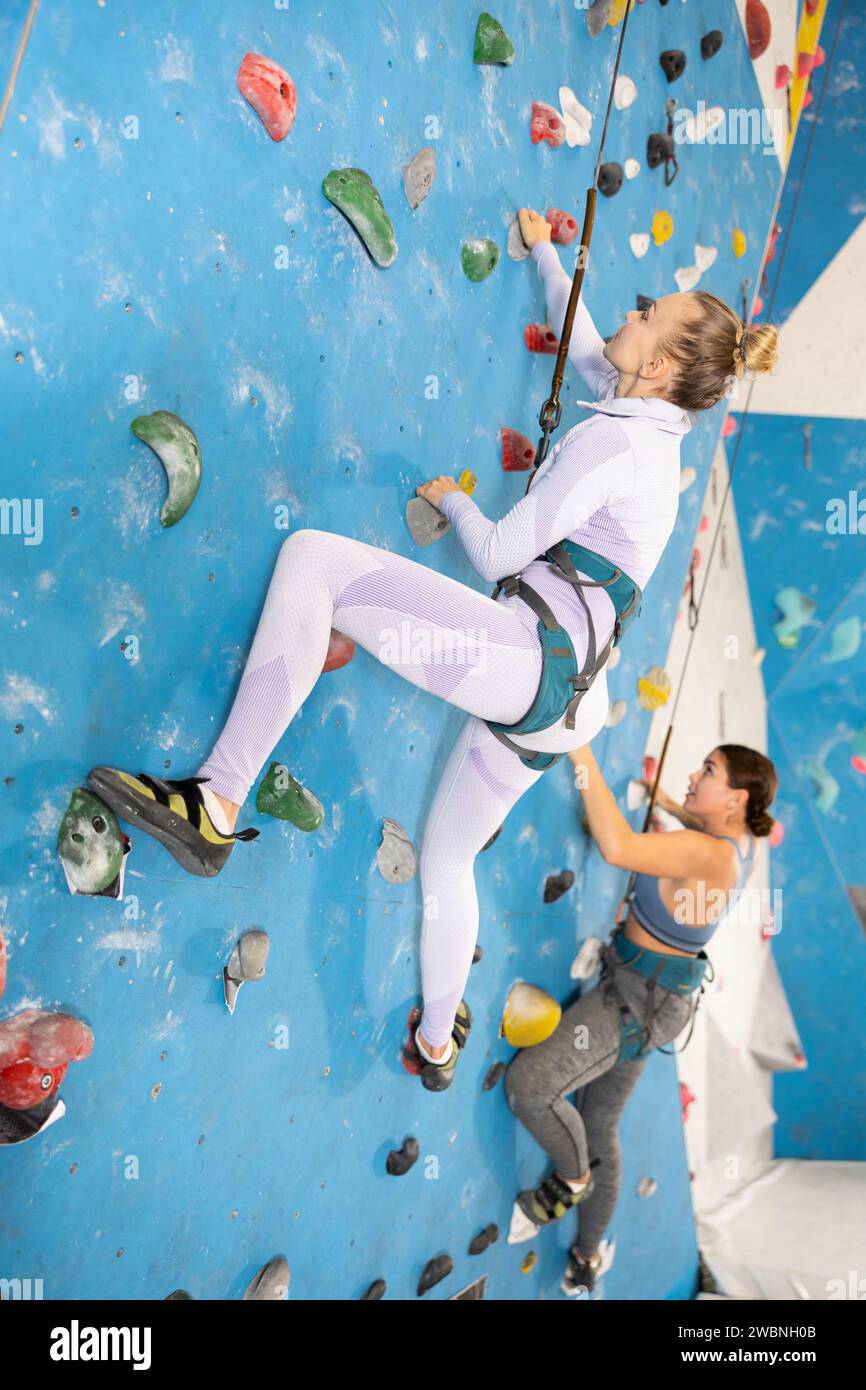Adult woman climbing wall with safety rope Stock Photo - Alamy