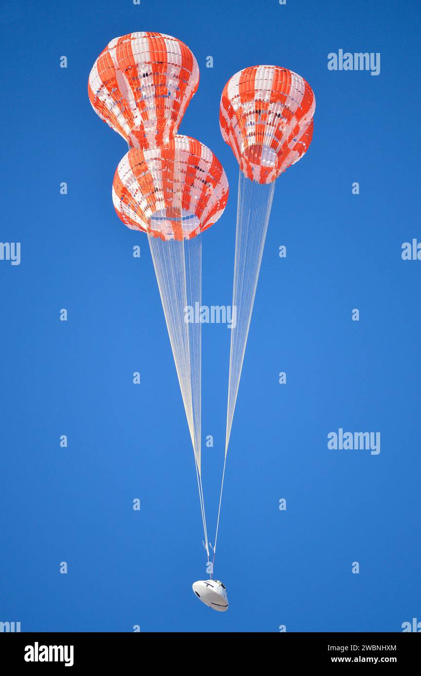 Orion’s three main orange and white parachutes help a representative ...