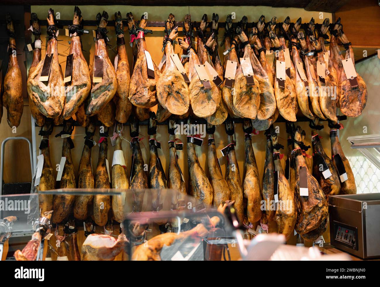 Row of dangling legs jamon with labels on showcase of butcher shop ...