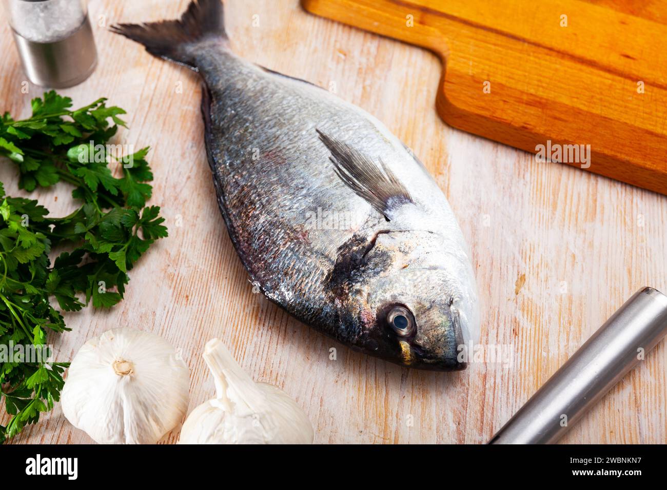 Raw whole dorado fish with garlic and greens, nobody Stock Photo - Alamy