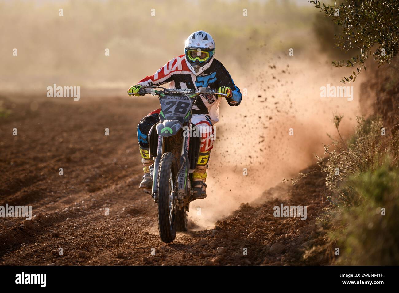 Motocross rider in action with speed to camera and lifting mud, rocks ...