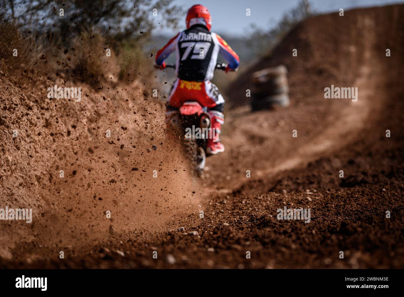 Motocross rider on his back leaving at high speed and kicking up mud ...