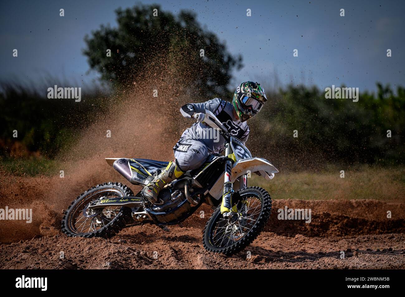 Motocross rider in action with speed to camera and lifting mud, rocks ...
