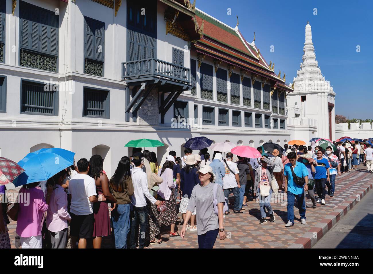 On a religious holiday, a long queue of local Thai people lines up to ...