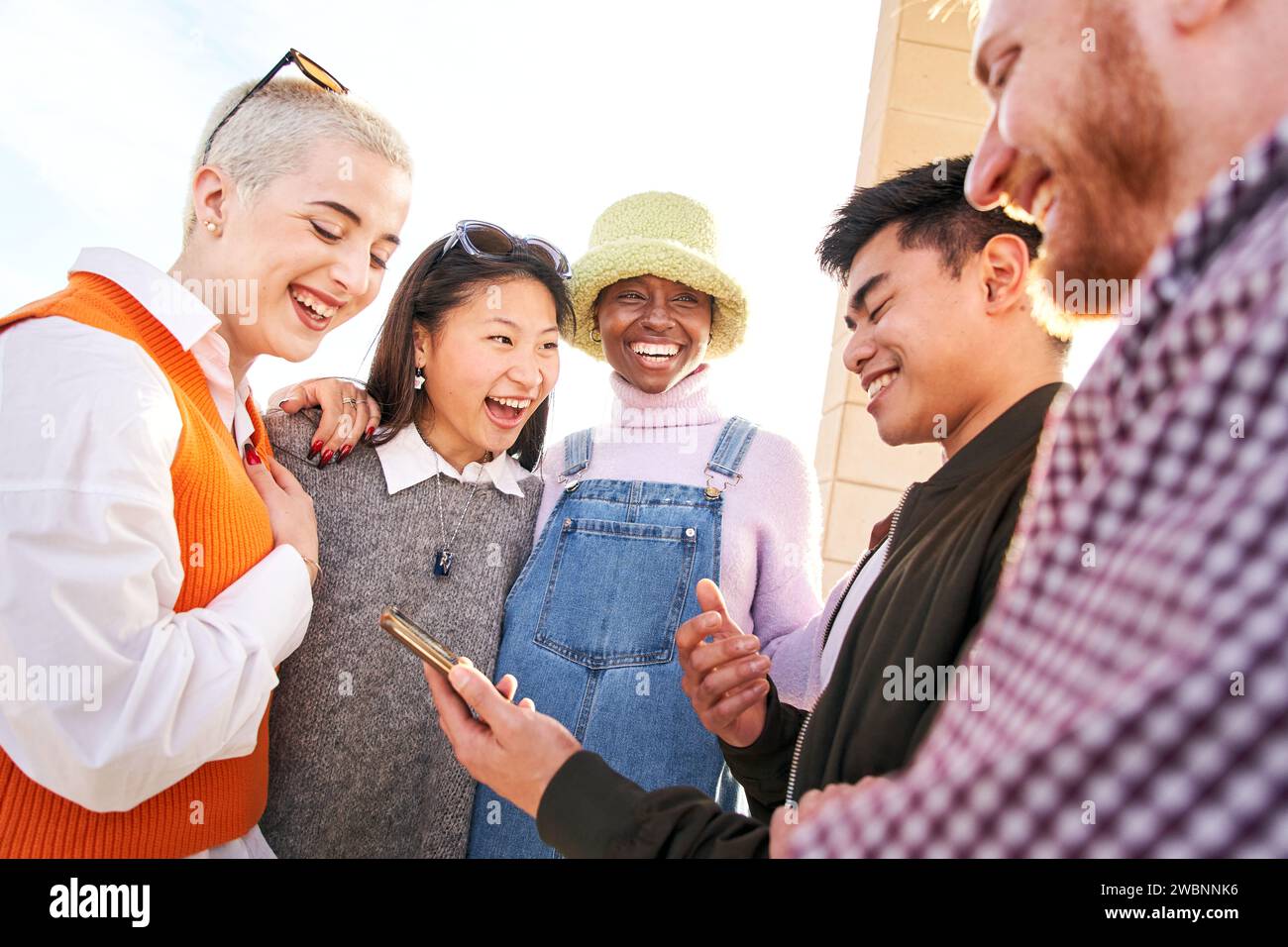 Smile multiracial group of students sharing mobile phone. They check ...