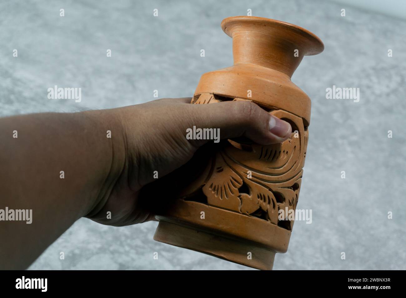A clay jug with reliefs on the side is held in the hand and placed on a ...