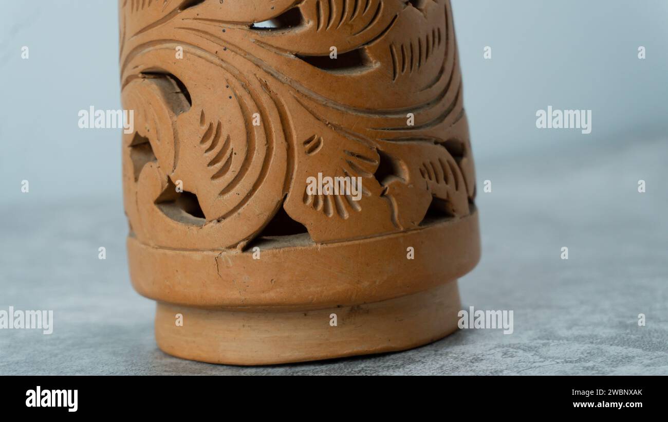A clay jug with reliefs on the sides is placed on a gray table with a ...